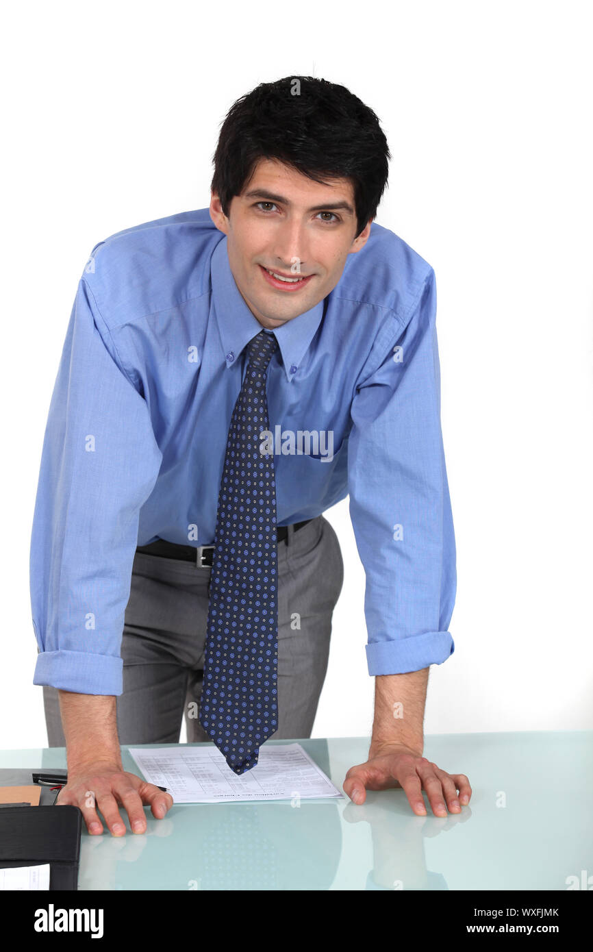 Young office worker leaning on his desk Stock Photo - Alamy