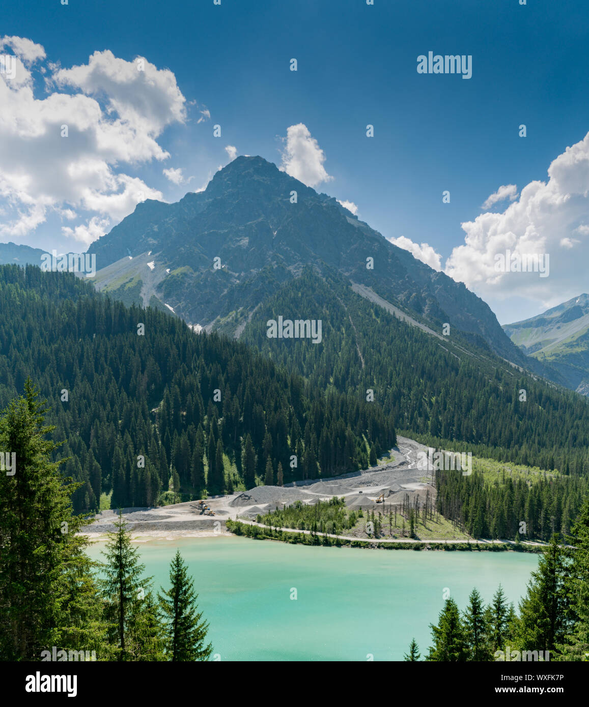 excavators and wheel loaders at the mouth of a mountain river move silt ...