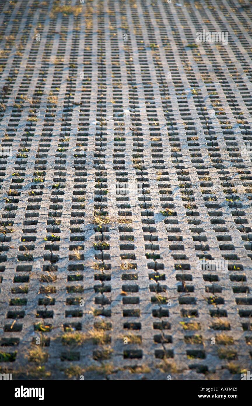 cement ground with holes and plants on a public parking Stock Photo - Alamy