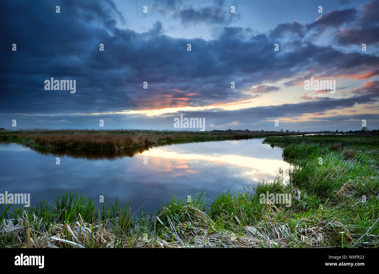 red sunbeams at sunset before storm over river, Drenthe, Netherlands ...