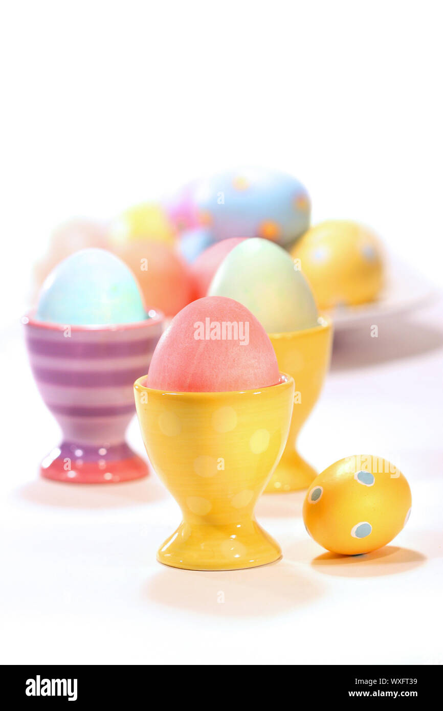 Egg cups with colored eggs on white background Stock Photo - Alamy