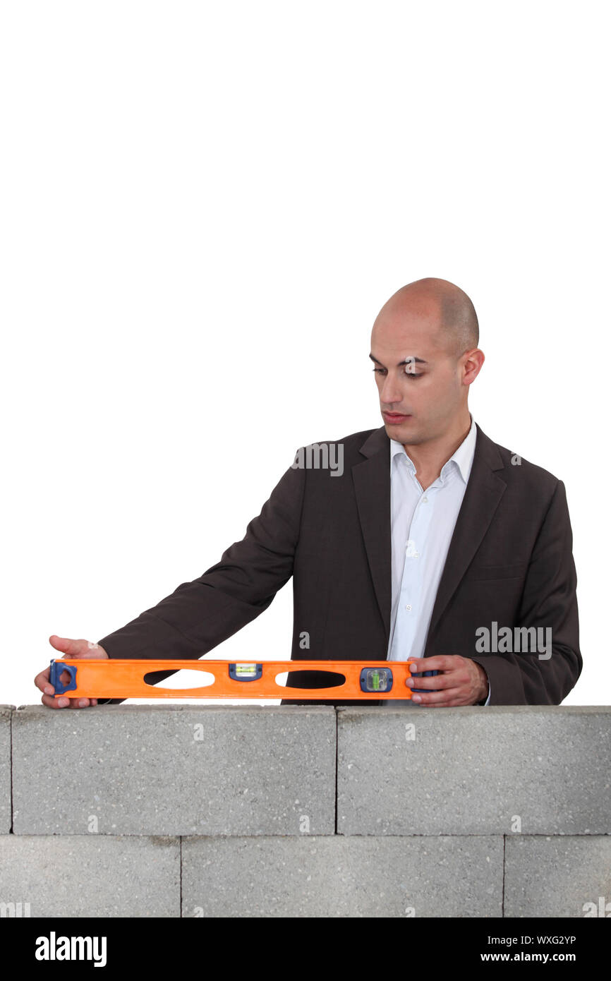 Man in a suit with a spirit level on a wall Stock Photo - Alamy