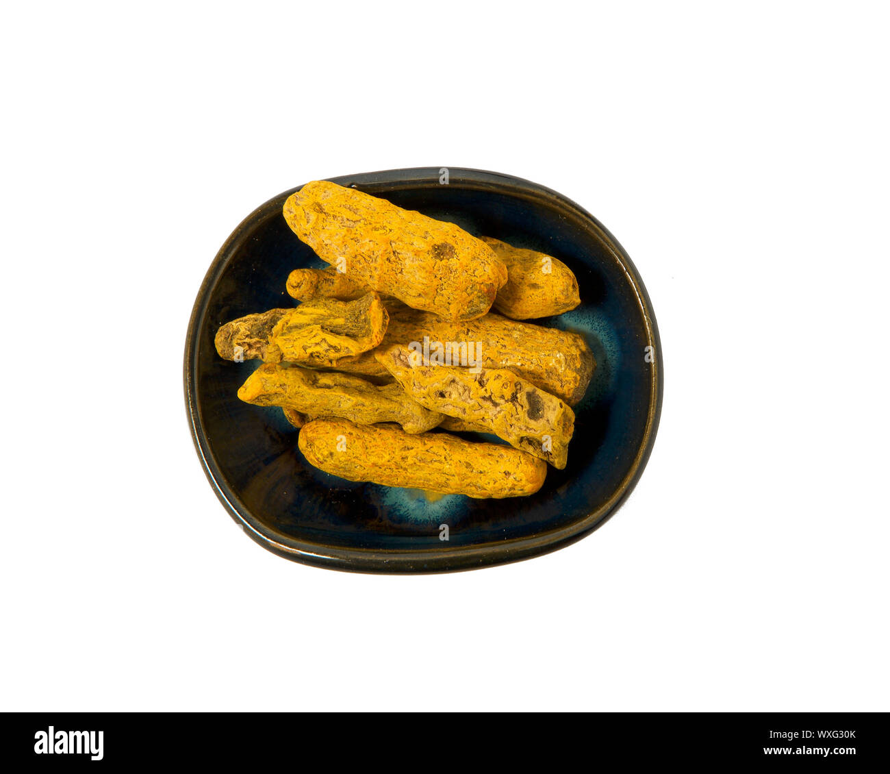 Dried turmeric root in a bowl isolated on a white background. Seasoning ...