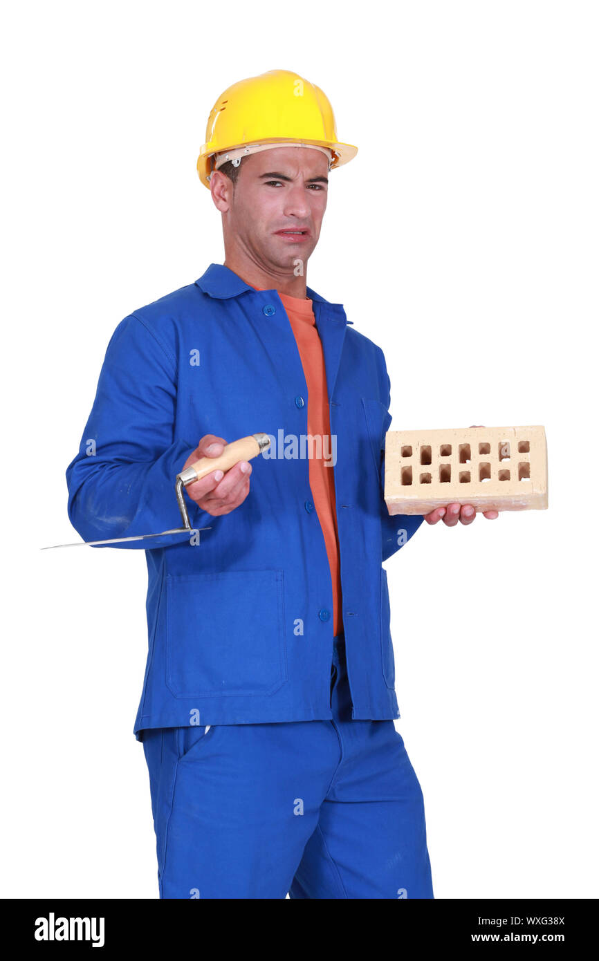 Confused mason holding brick and trowel Stock Photo - Alamy