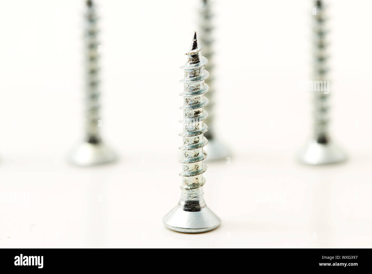 one screw standing in front of three on white background Stock Photo ...