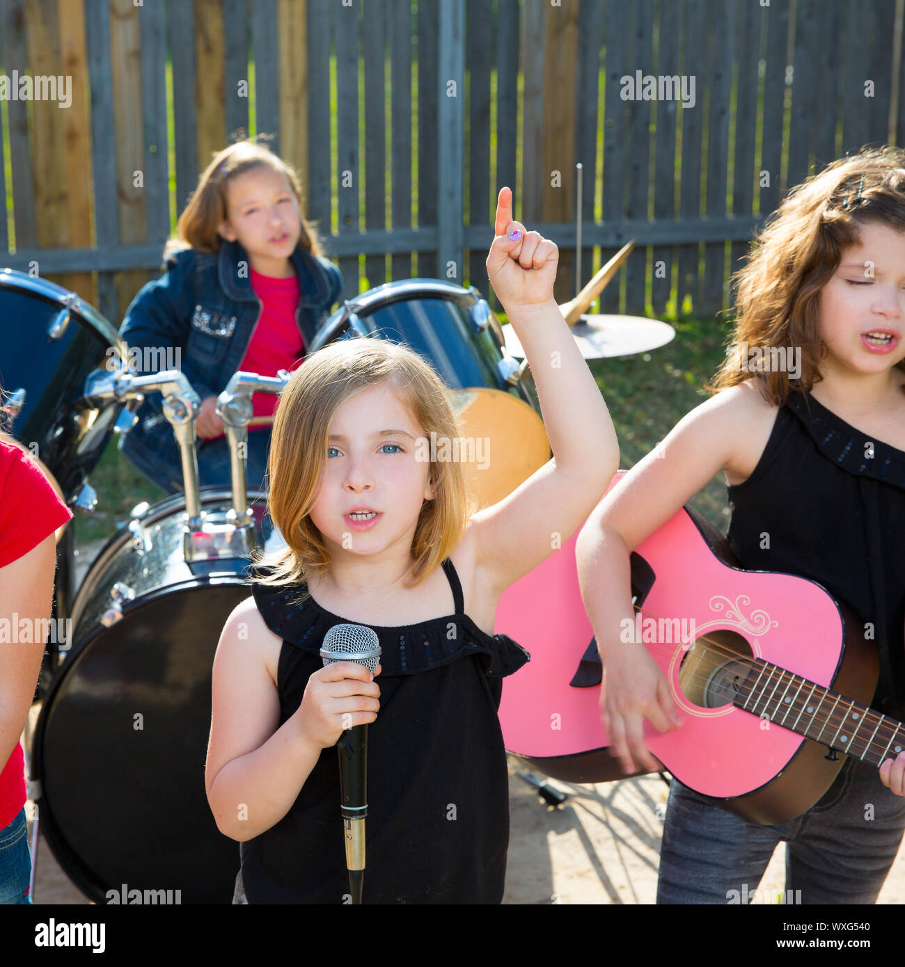 Blond kid singer girl singing playing live band in backyard concert ...