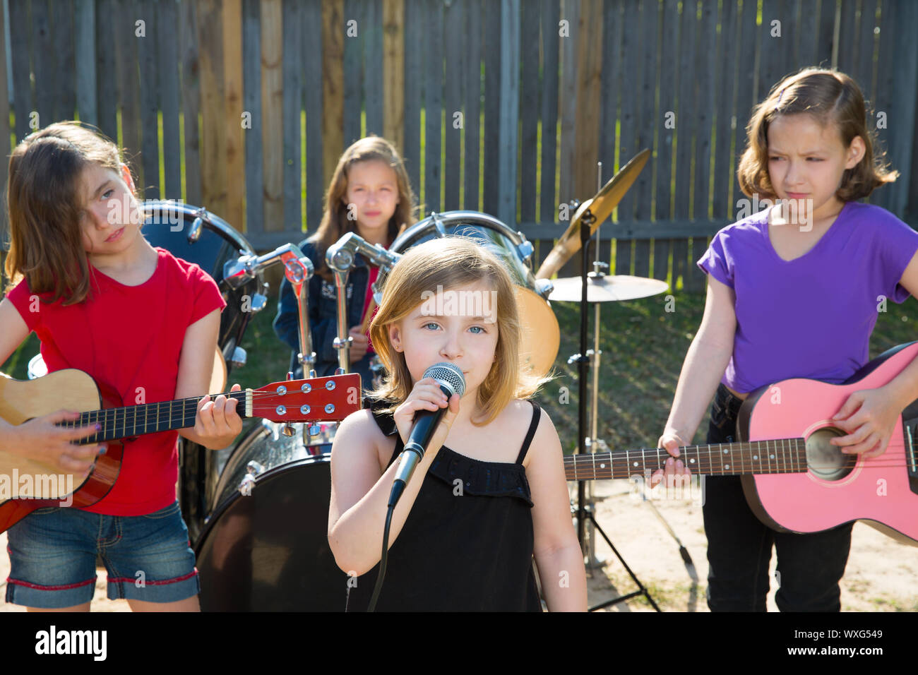 Blond kid singer girl singing playing live band in backyard concert ...