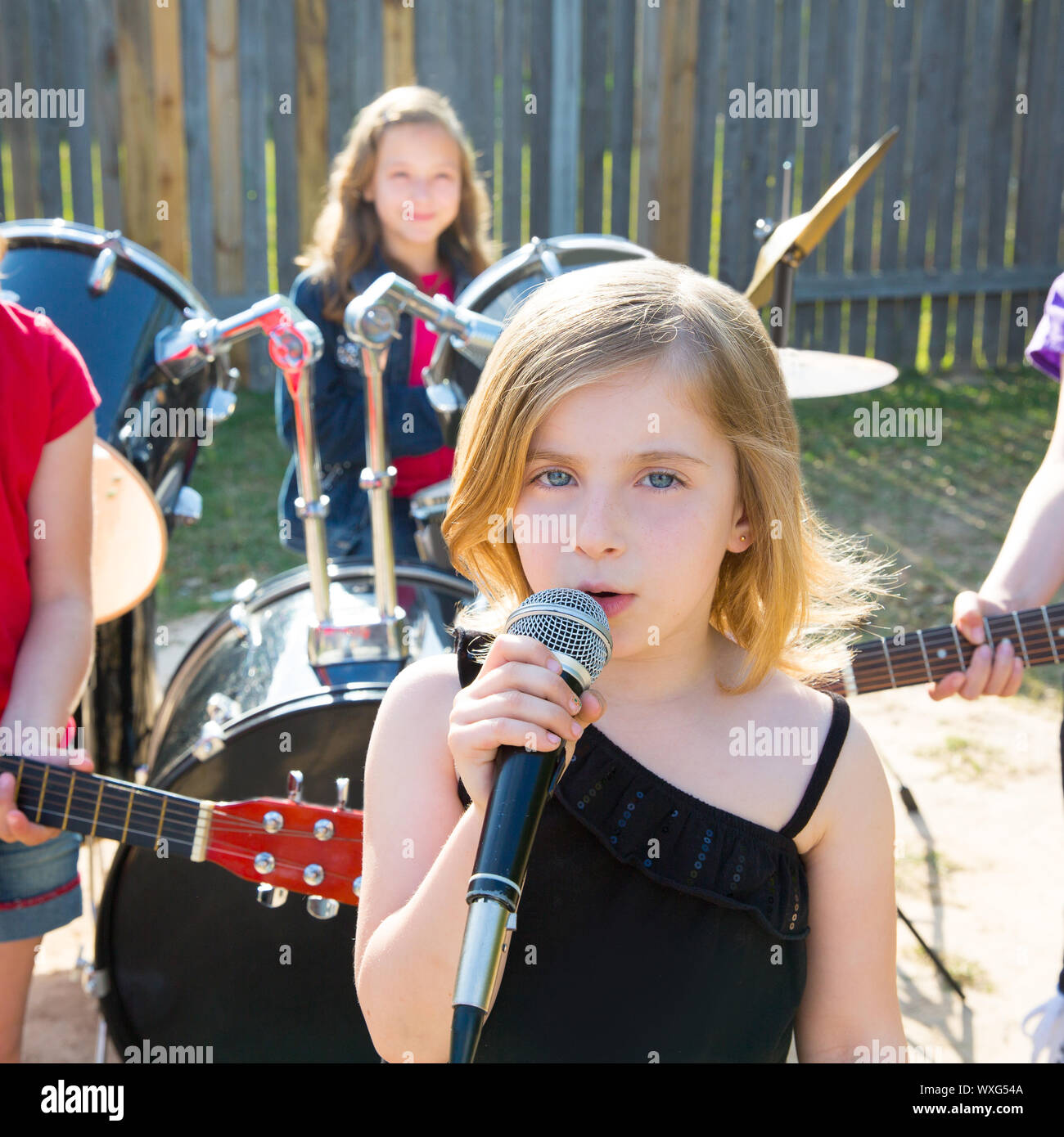 Blond kid singer girl singing playing live band in backyard concert ...