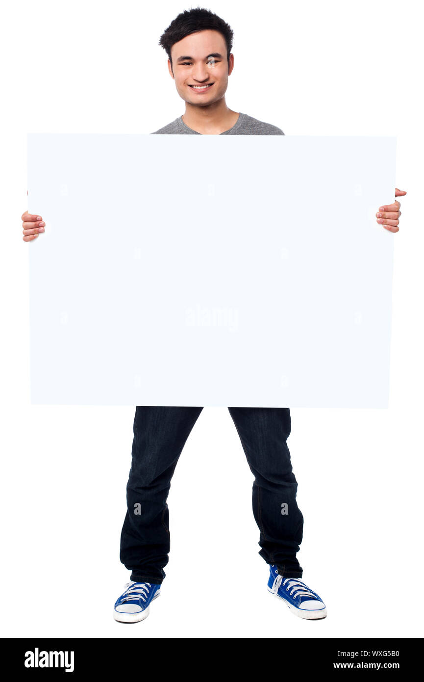 Smiling young guy holding white poster Stock Photo - Alamy