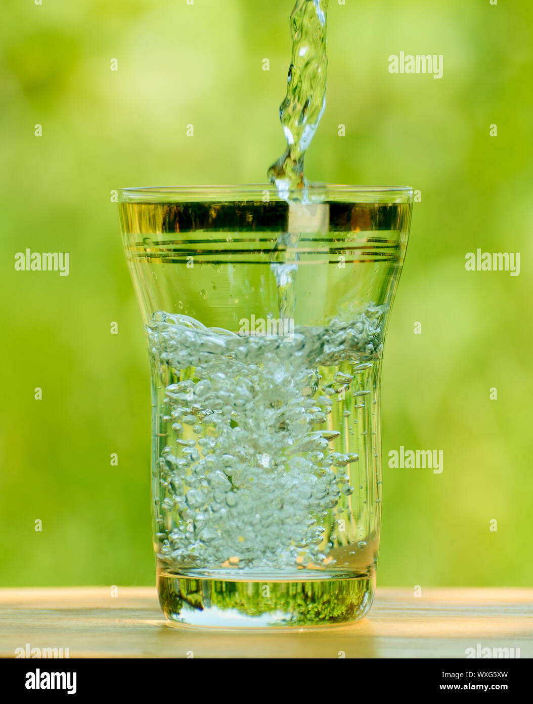 Pouring Water into a Glass against the Green Nature Background Stock ...