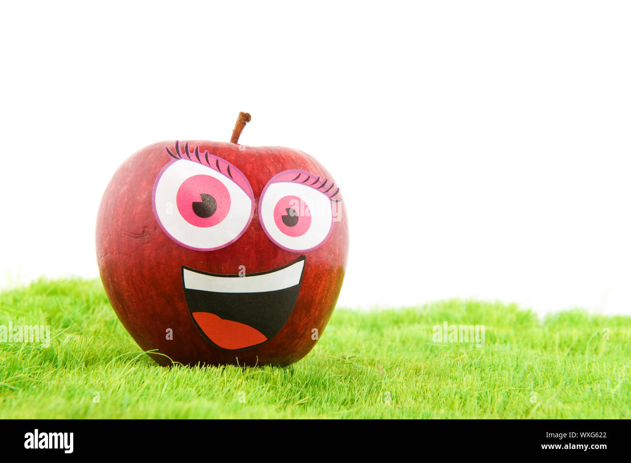 Funny apple with a face in the grass Stock Photo - Alamy