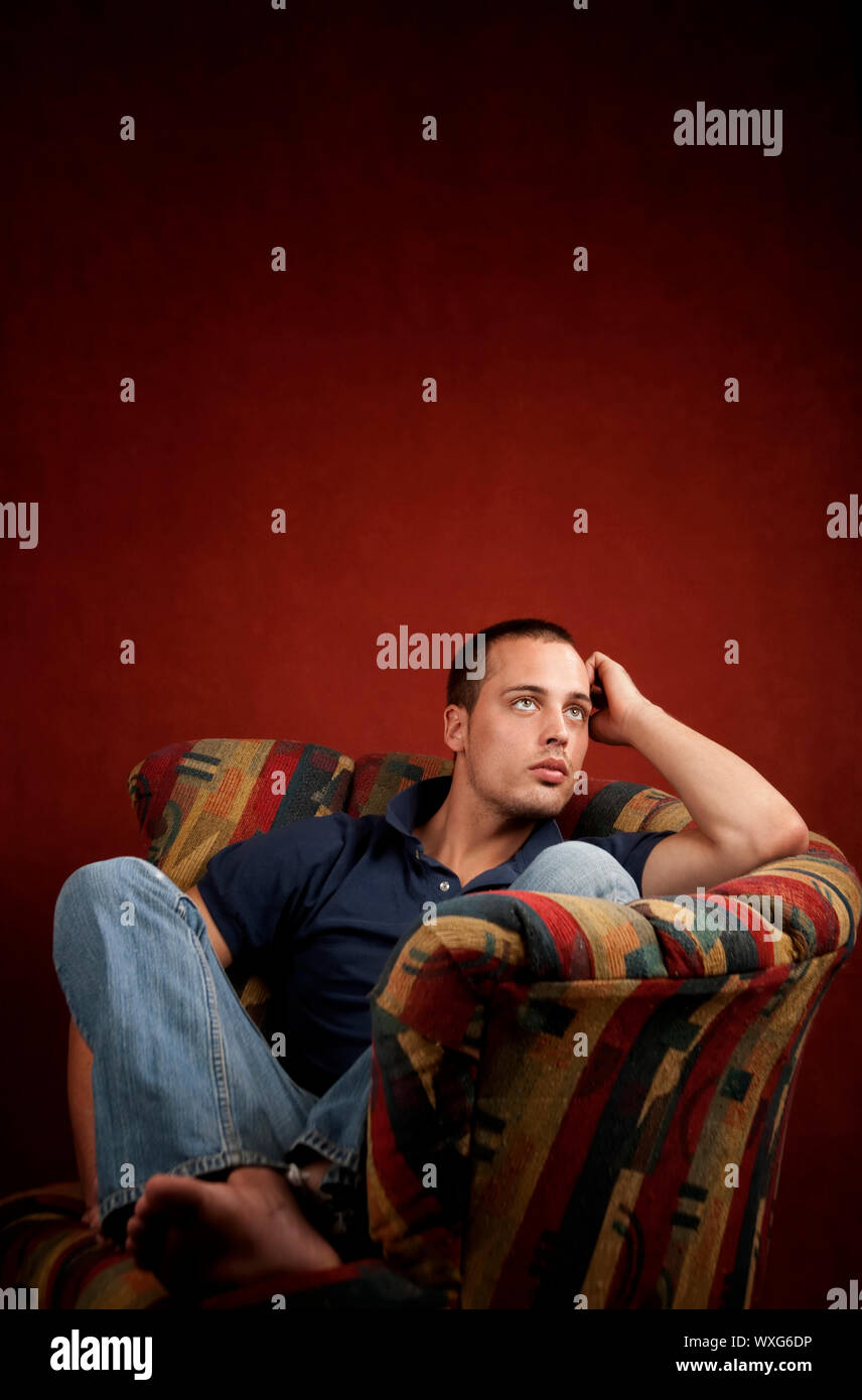 Handsome young man reclining in a colorful chair Stock Photo - Alamy
