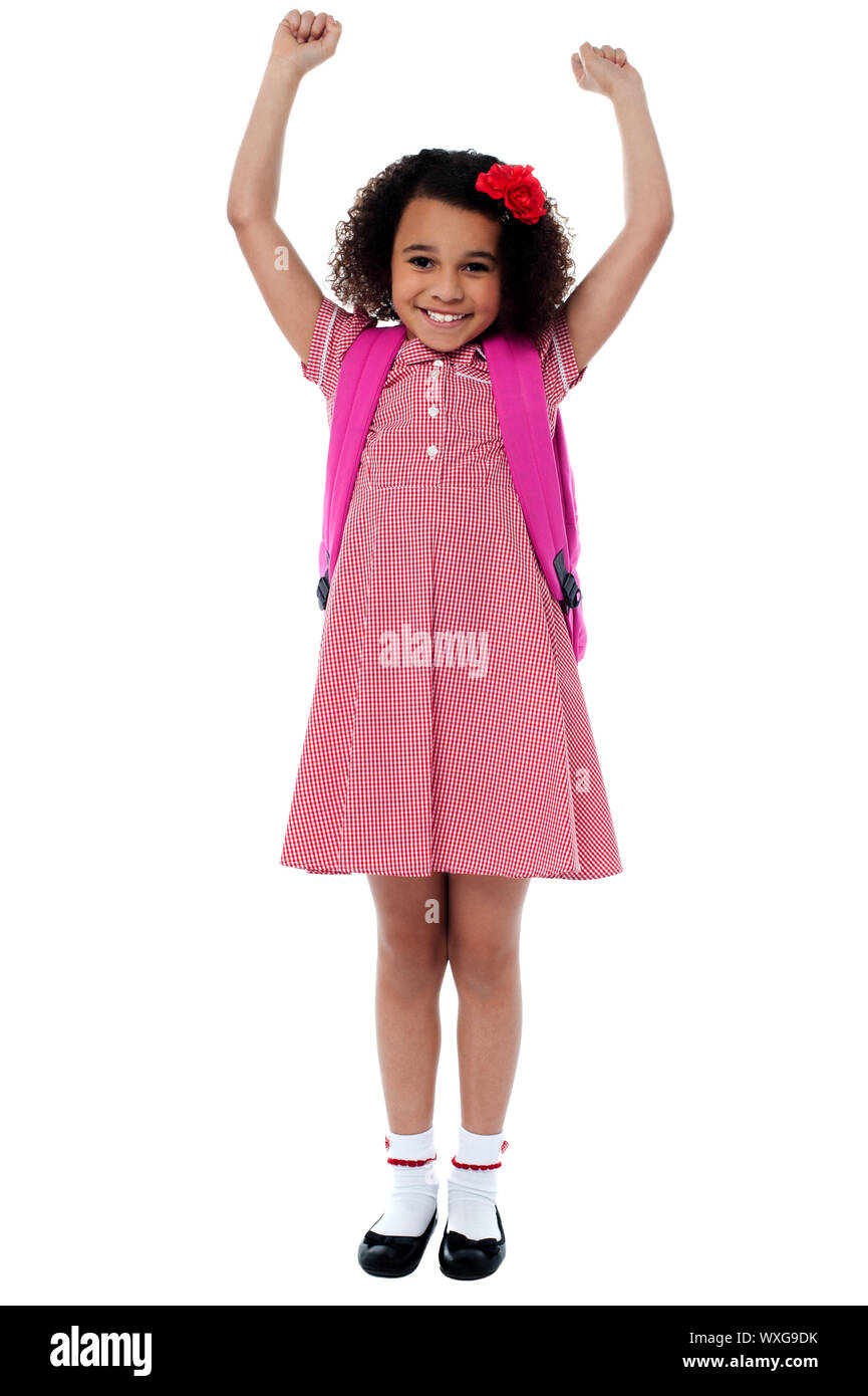 Enthusiastic elementary school girl posing with arms raised up ...
