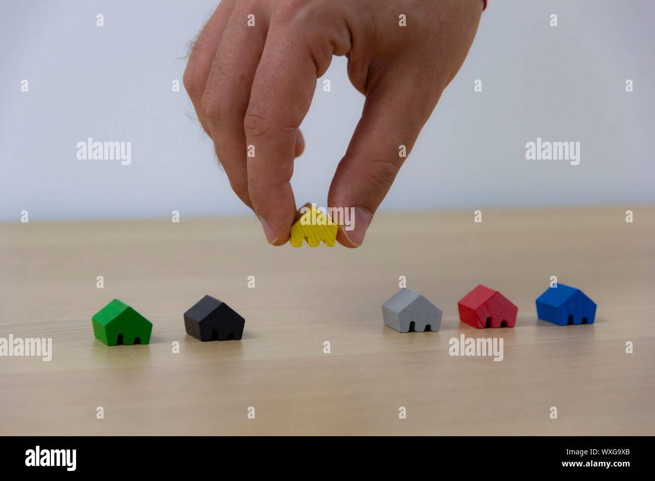 Hand select home, concept different colored game pieces Stock Photo - Alamy