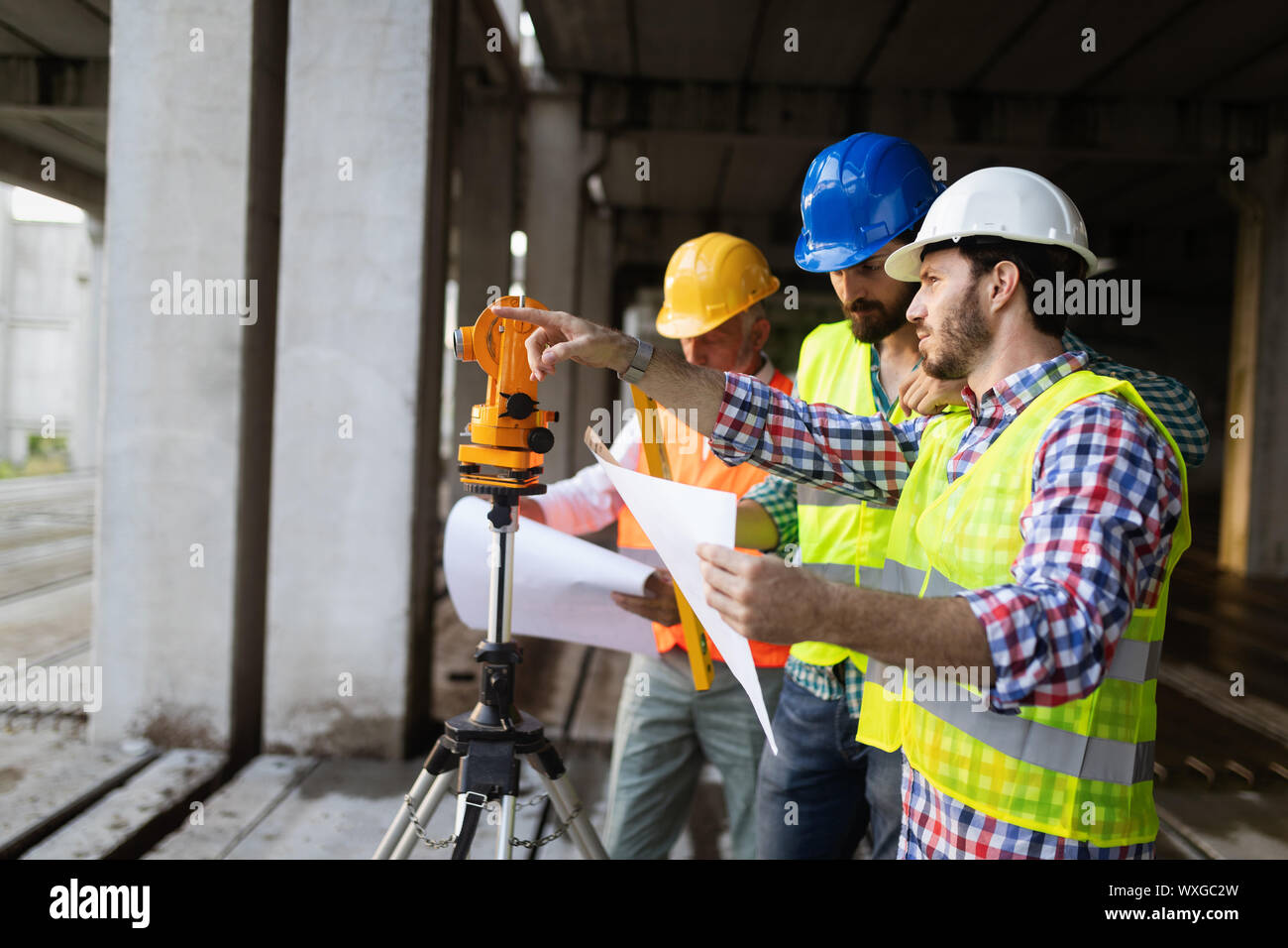 Engineer, foreman and worker discussing in building construction site ...