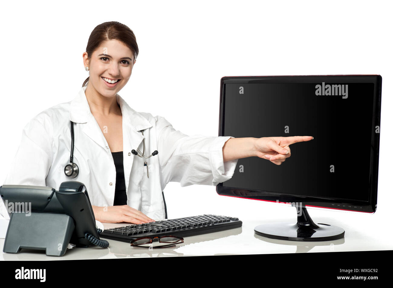 Smiling female physician pointing at computer screen sitting in her ...