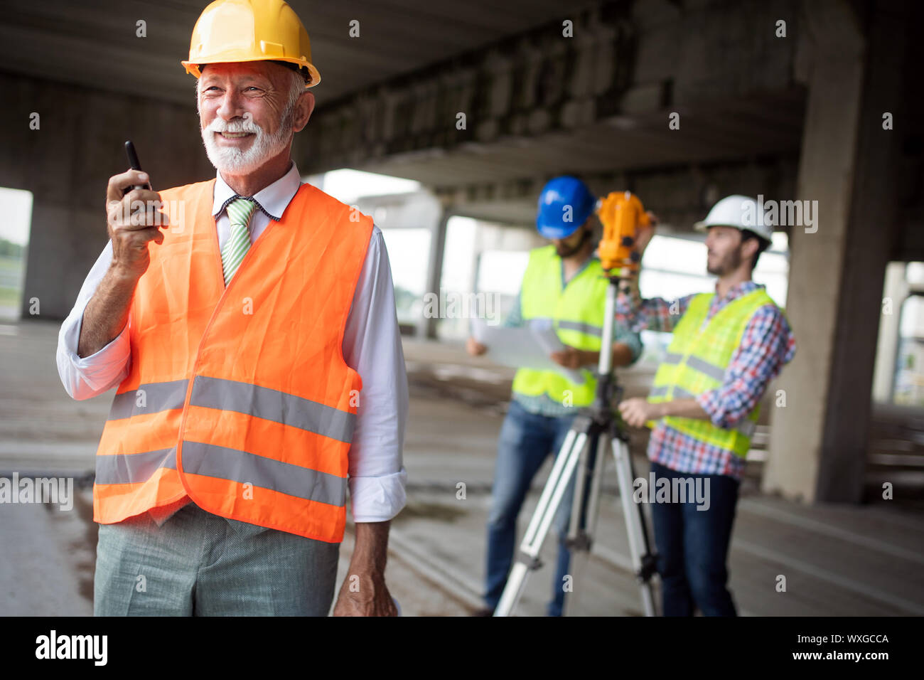 Engineer, foreman and worker discussing in building construction site ...
