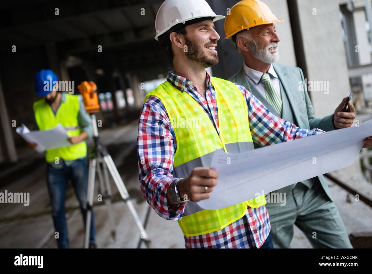 Engineer, foreman and worker discussing in building construction site ...