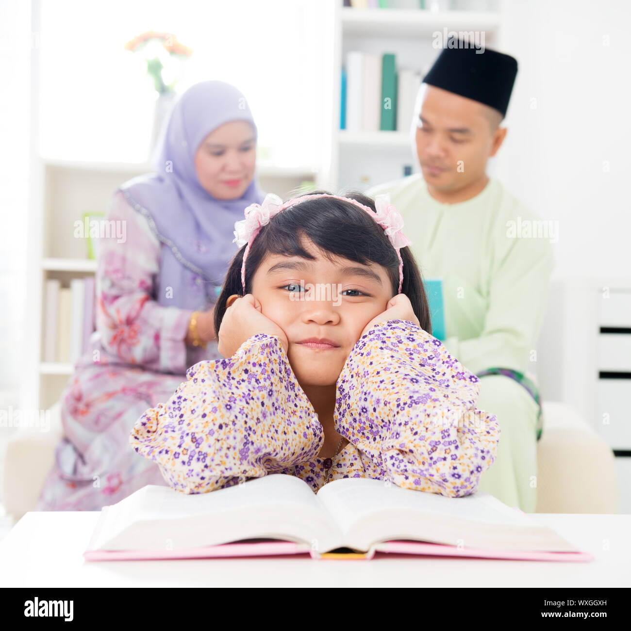 Malay girl reading book. Southeast Asian family at home. Muslim parents ...