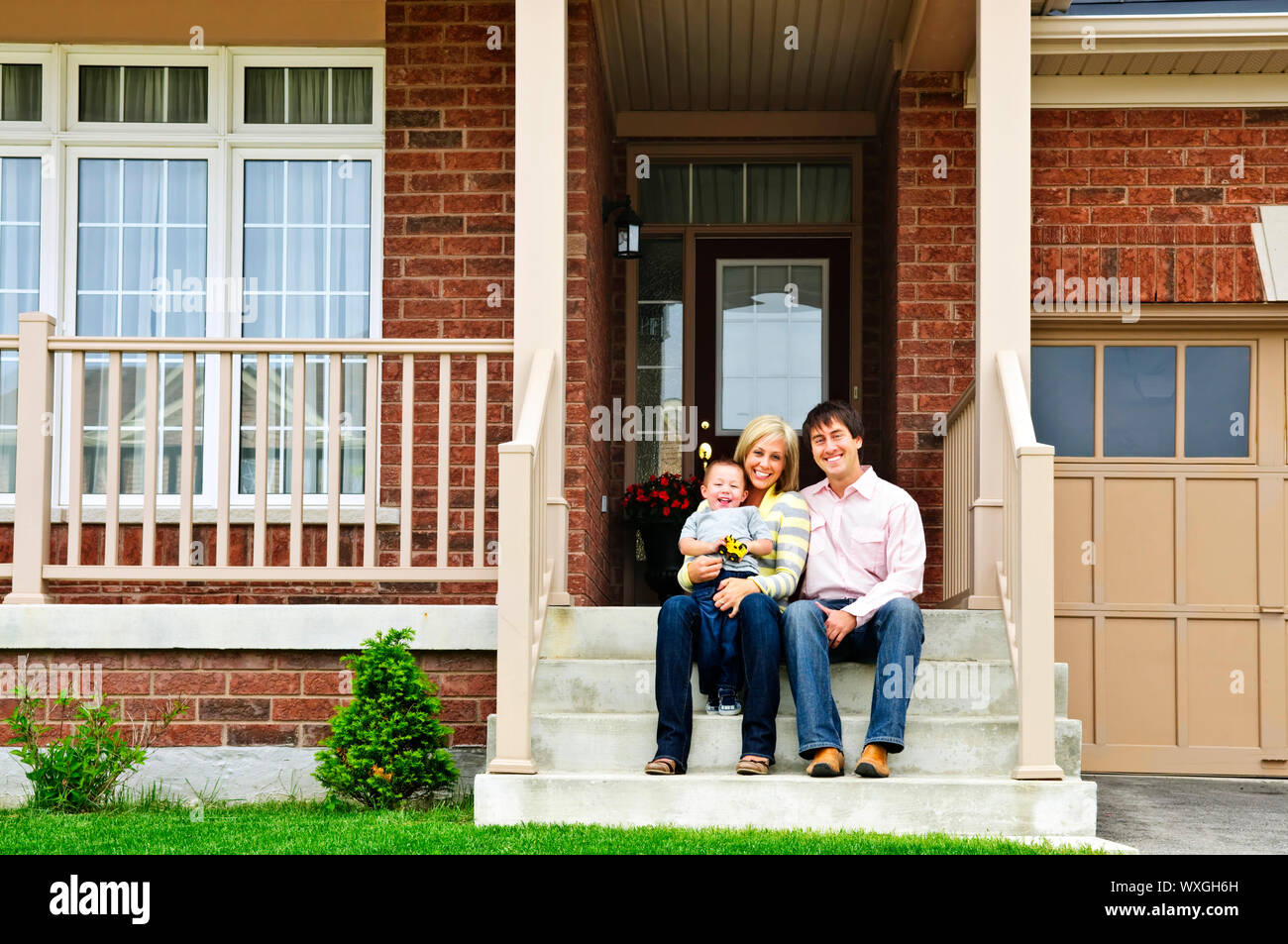 Young family sitting on front steps of house Stock Photo - Alamy
