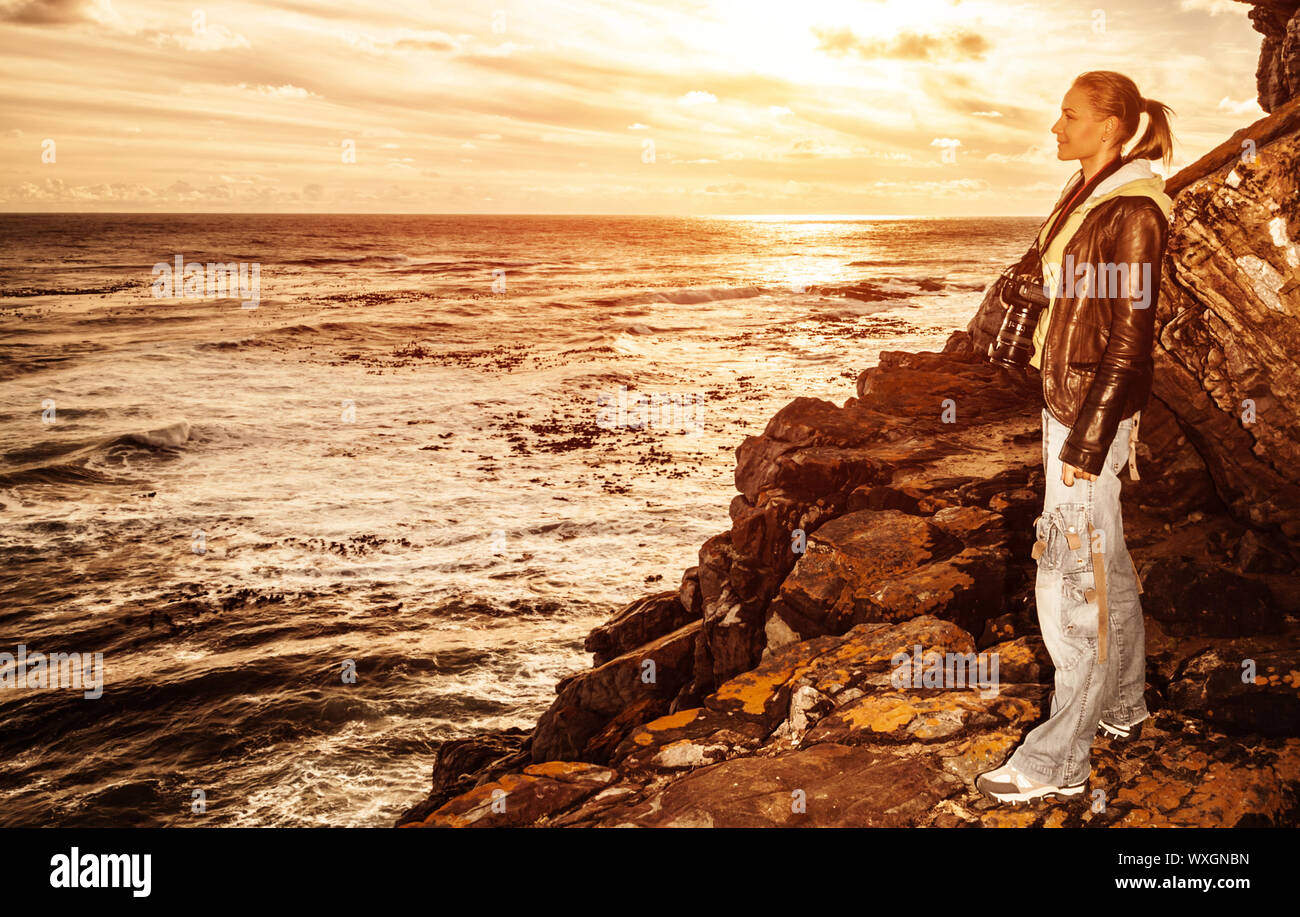 Tourist girl on sunset on the cliff Stock Photo - Alamy