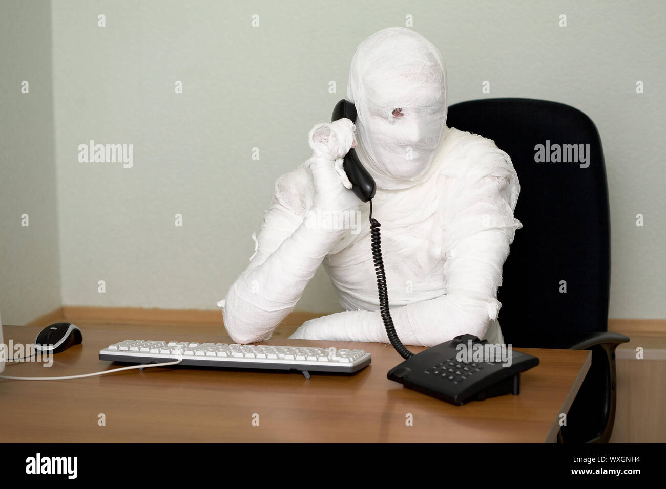 Bandaged boss calling on telephone in office Stock Photo - Alamy