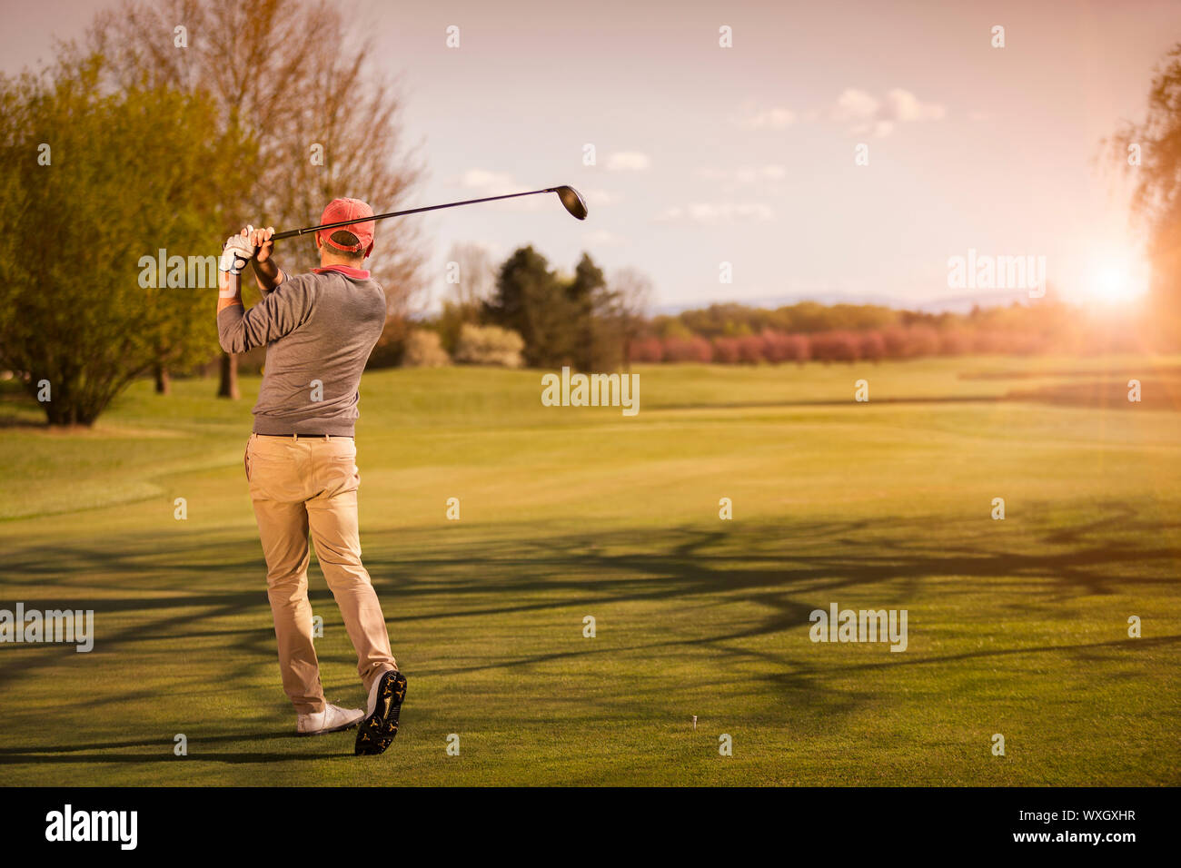 Male golf player at sunset Stock Photo - Alamy
