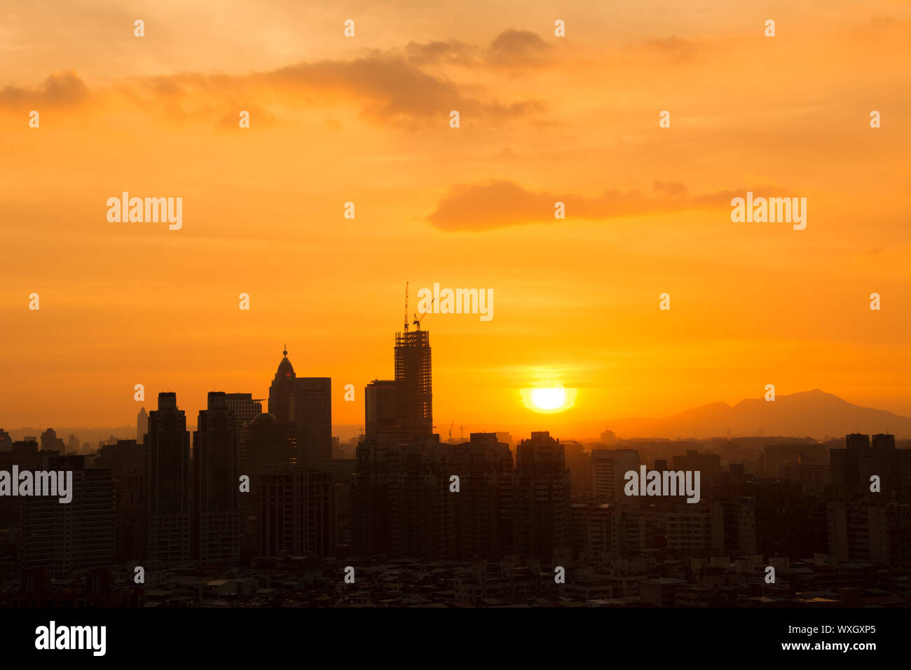 Sunset cityscape with dramatic clouds in orange and yellow color in ...