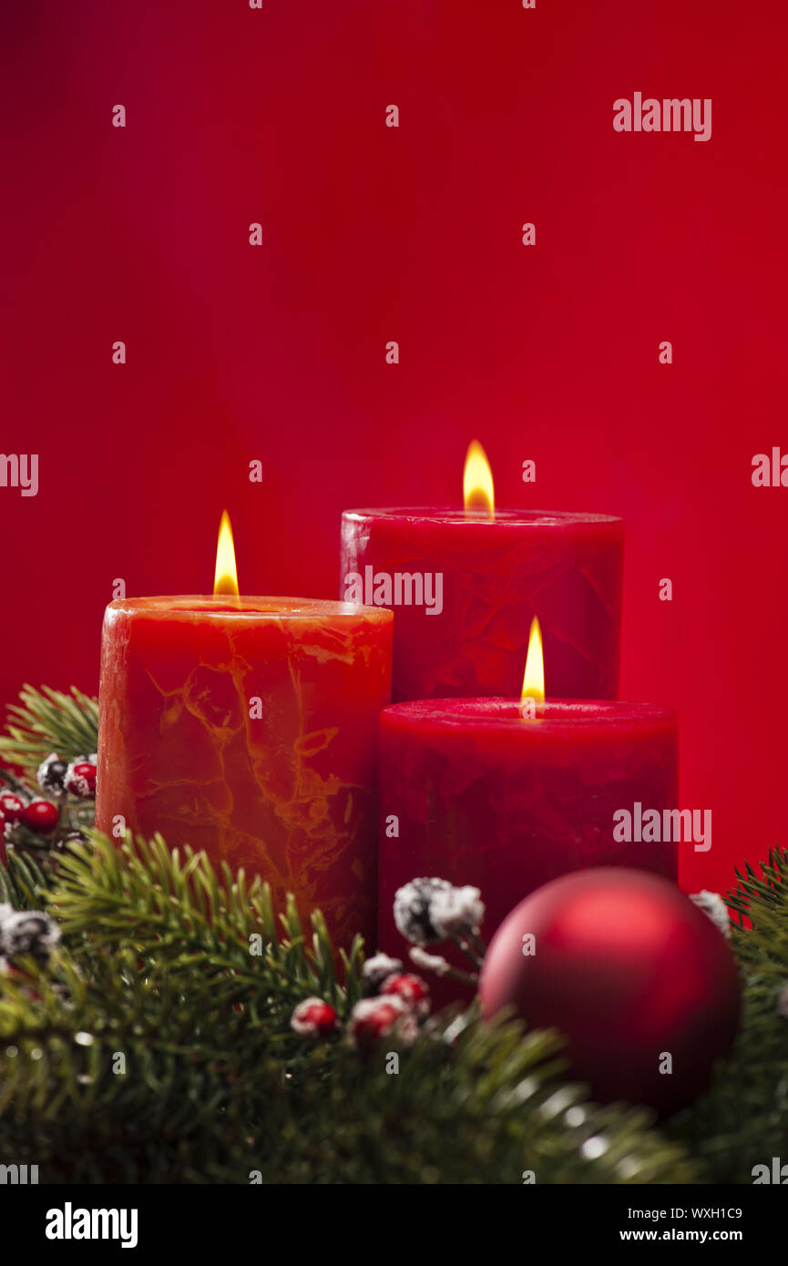 Red advent flower arrangement with burning candles Stock Photo - Alamy