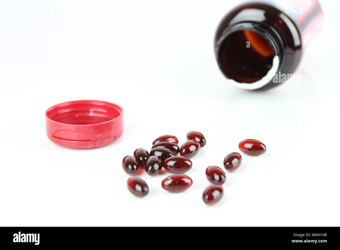 Red gel capsules isolated on white background with a bottle at the ...