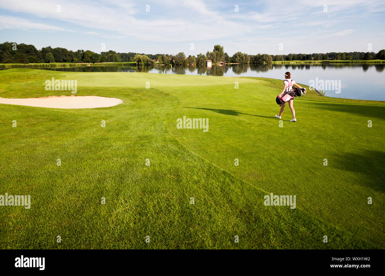 Girl golfer walking on golf course with golf bag Stock Photo - Alamy