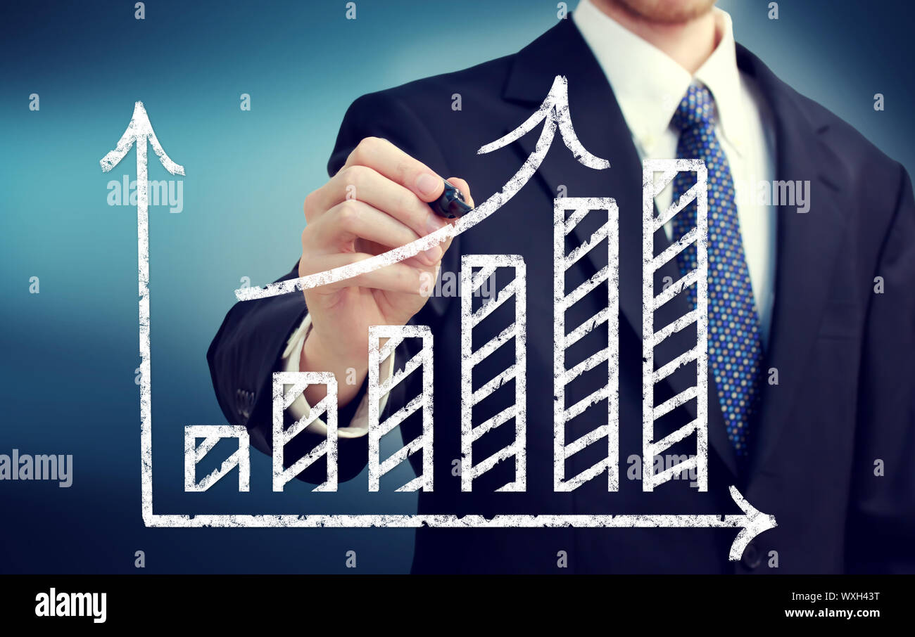 Businessman drawing a rising arrow over a bar graph Stock Photo - Alamy