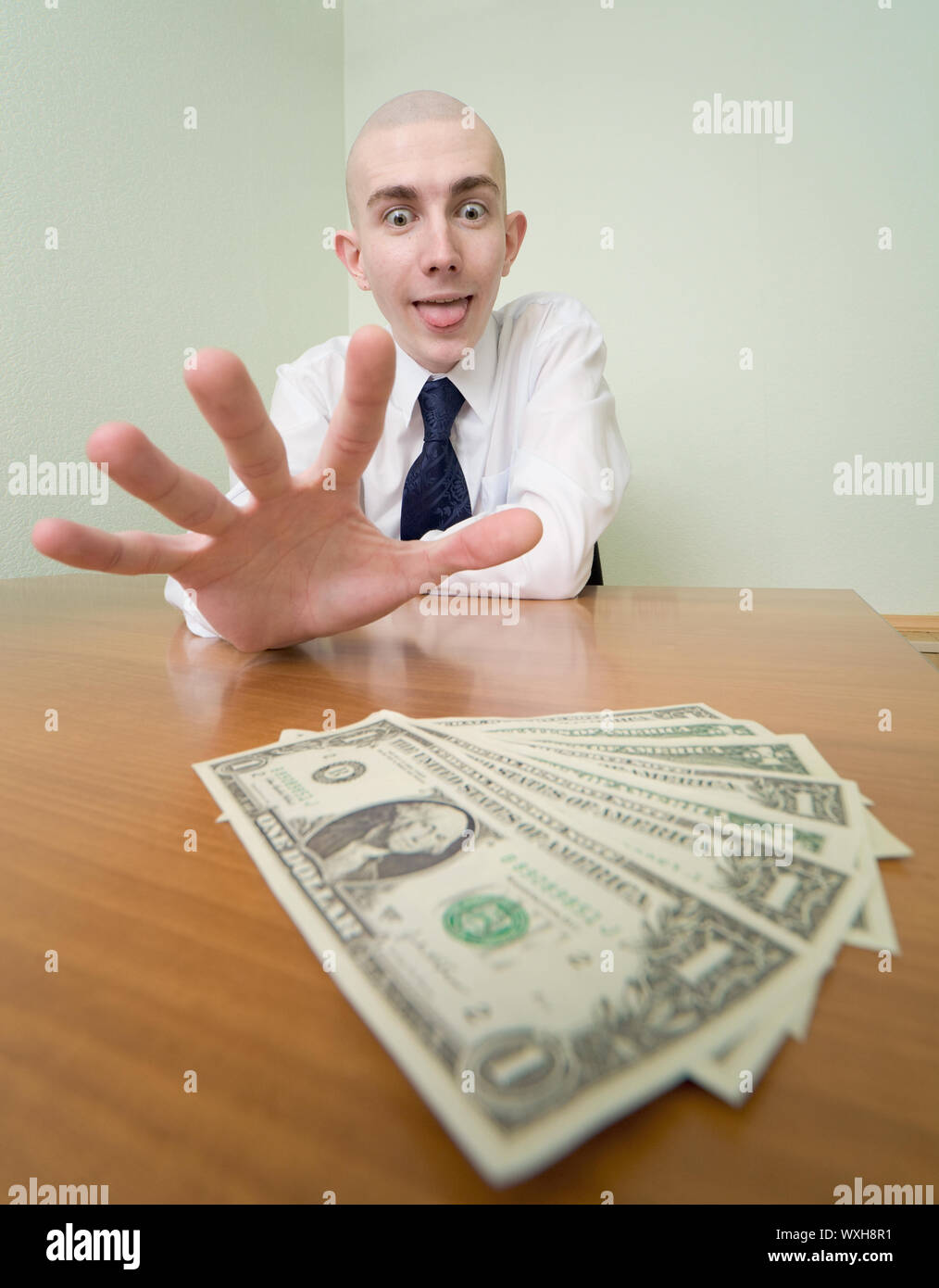 Young man reaches for a batch of money lying on a table Stock Photo - Alamy