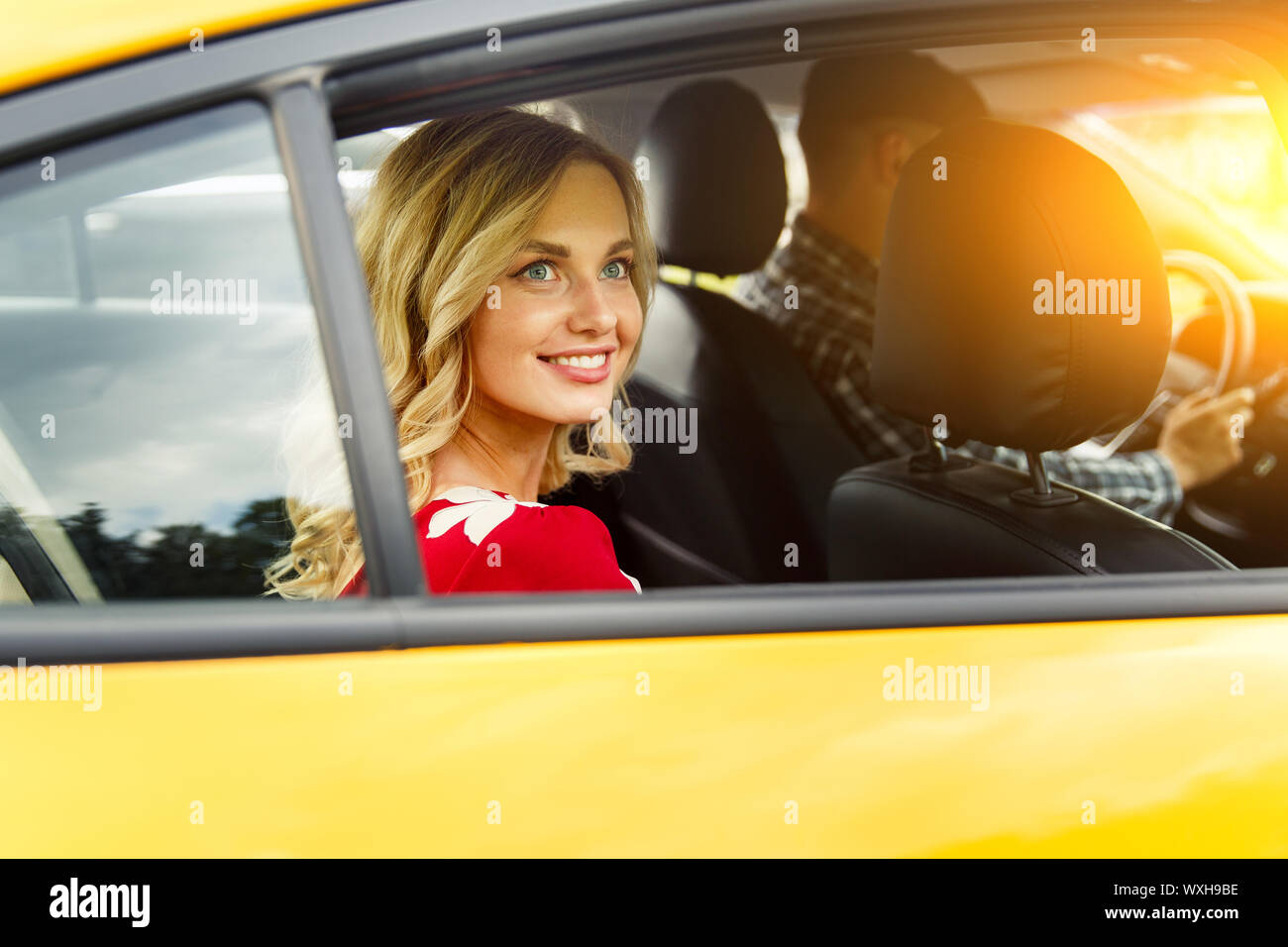 Photo of happy woman sitting in back seat of yellow taxi in summer ...