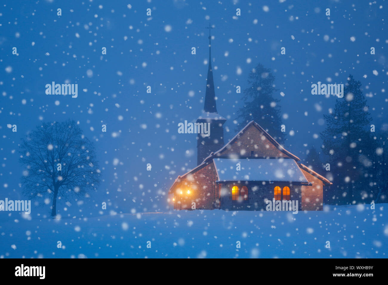 Illuminated chapel in the snowfall at night. Kandersteg, Switzerland ...