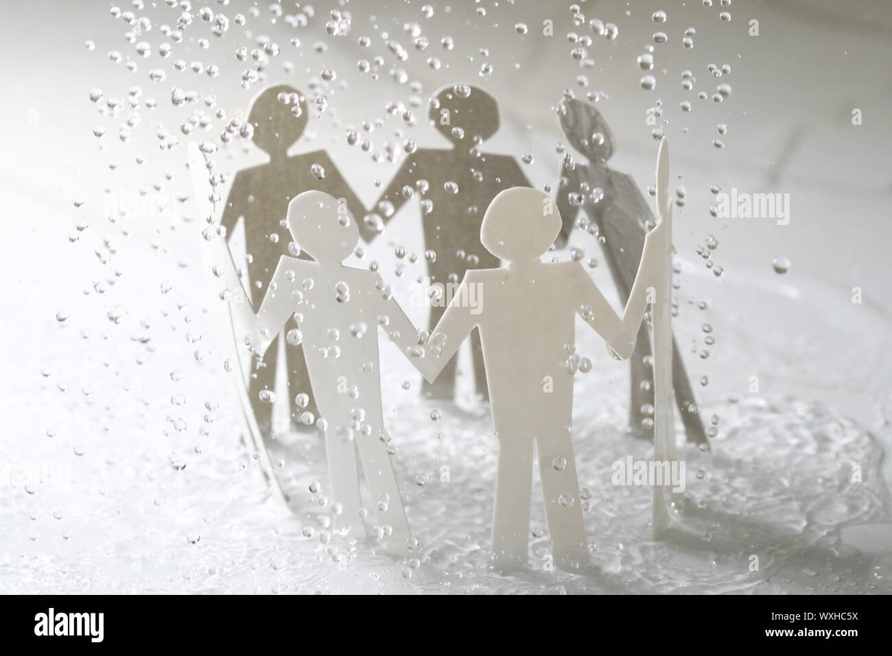 paper team linked together under rain weather concept Stock Photo - Alamy