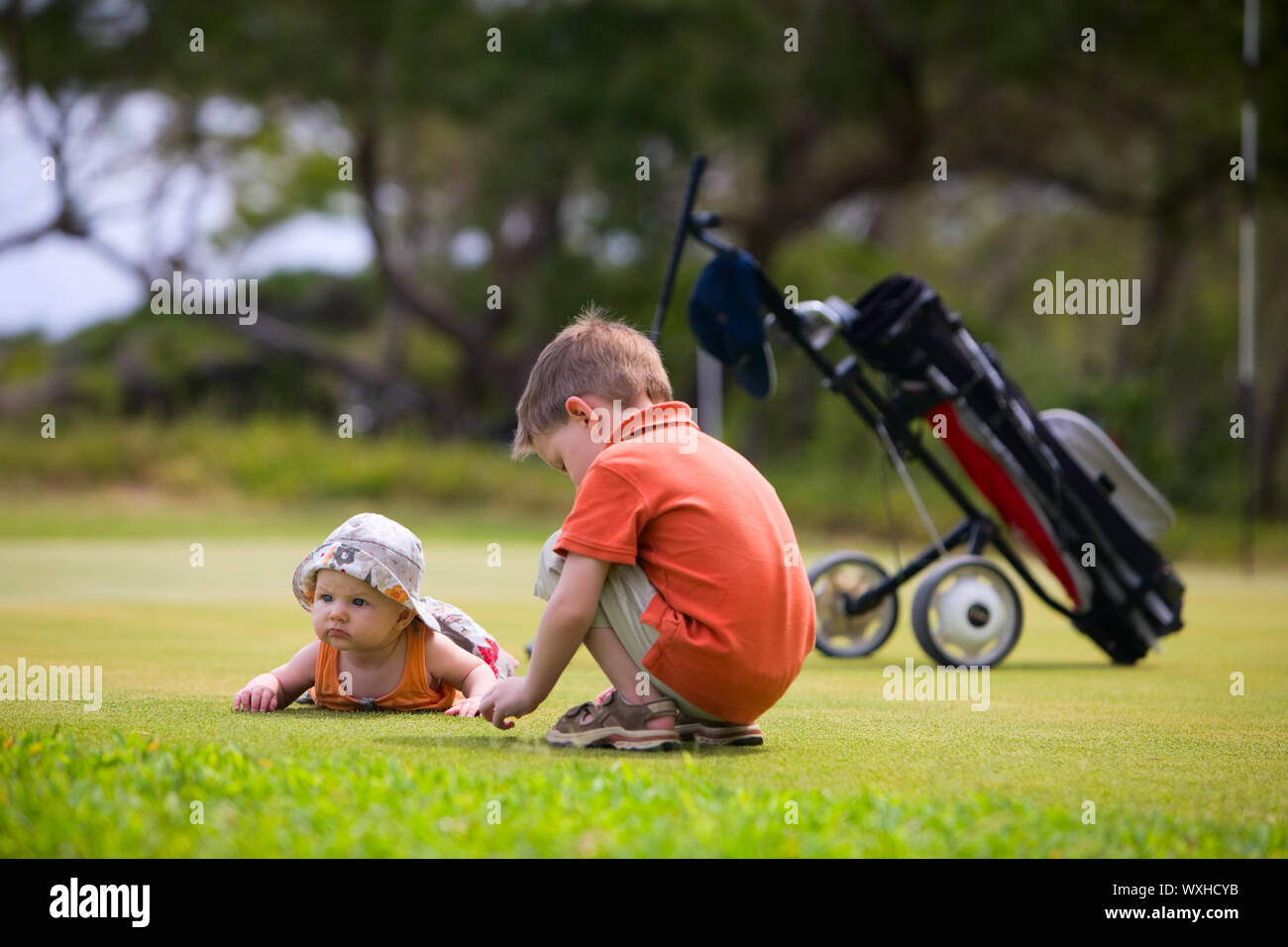 Two adorable kids playing on golf field waiting Stock Photo - Alamy