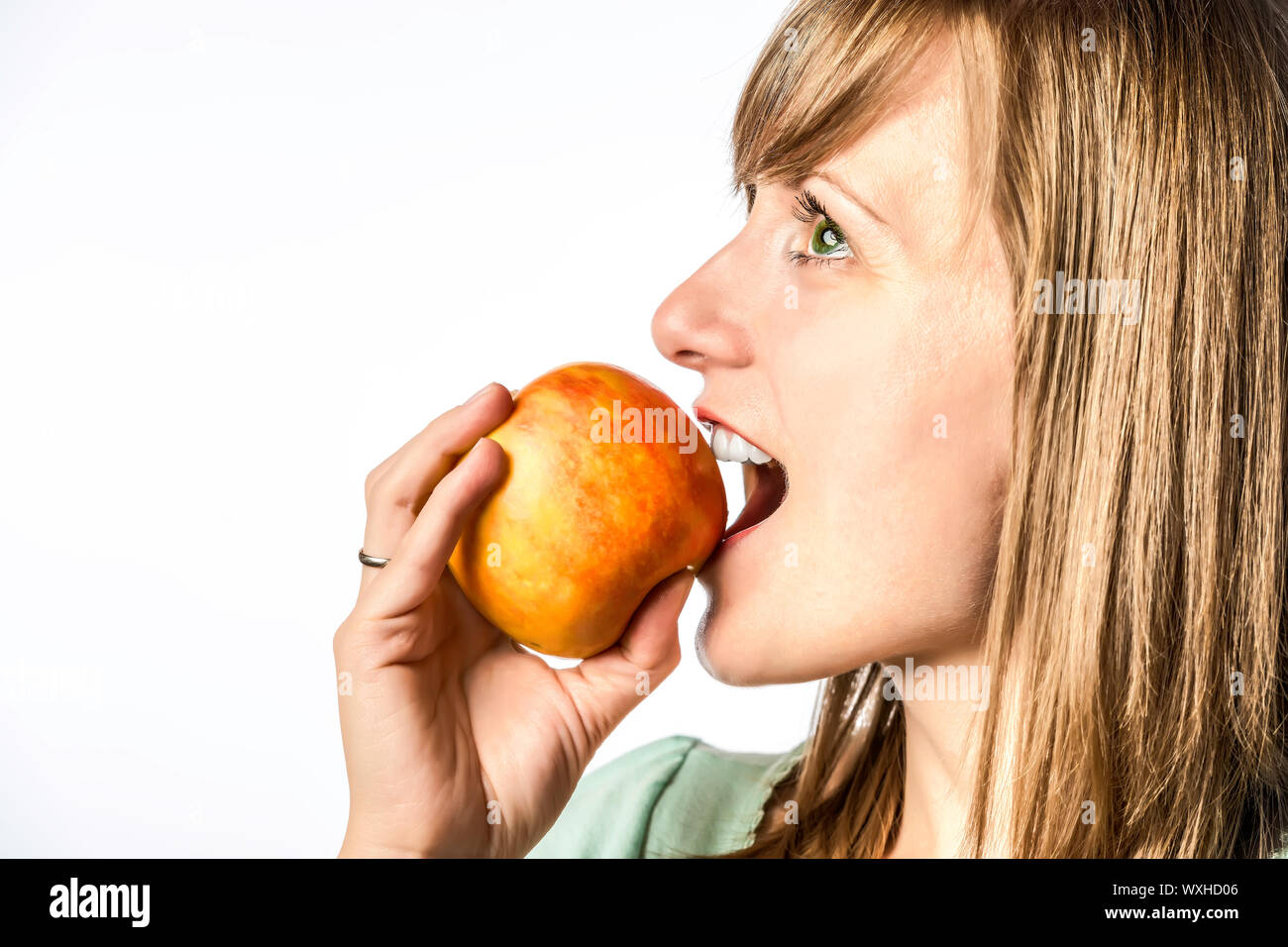 Portrait of a young girl biting into a red yellow apple, isolated on ...