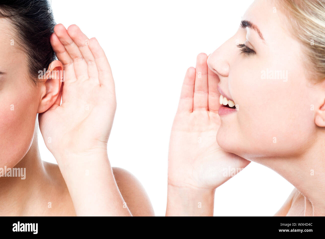 Smiling girl whispering into her friends ear Stock Photo - Alamy