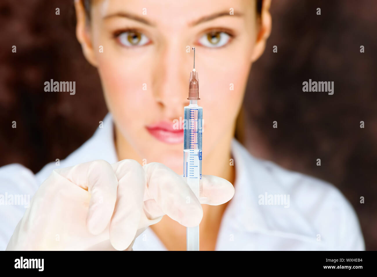 Handsome female nurse holding syringe and looking at a drop on the top ...