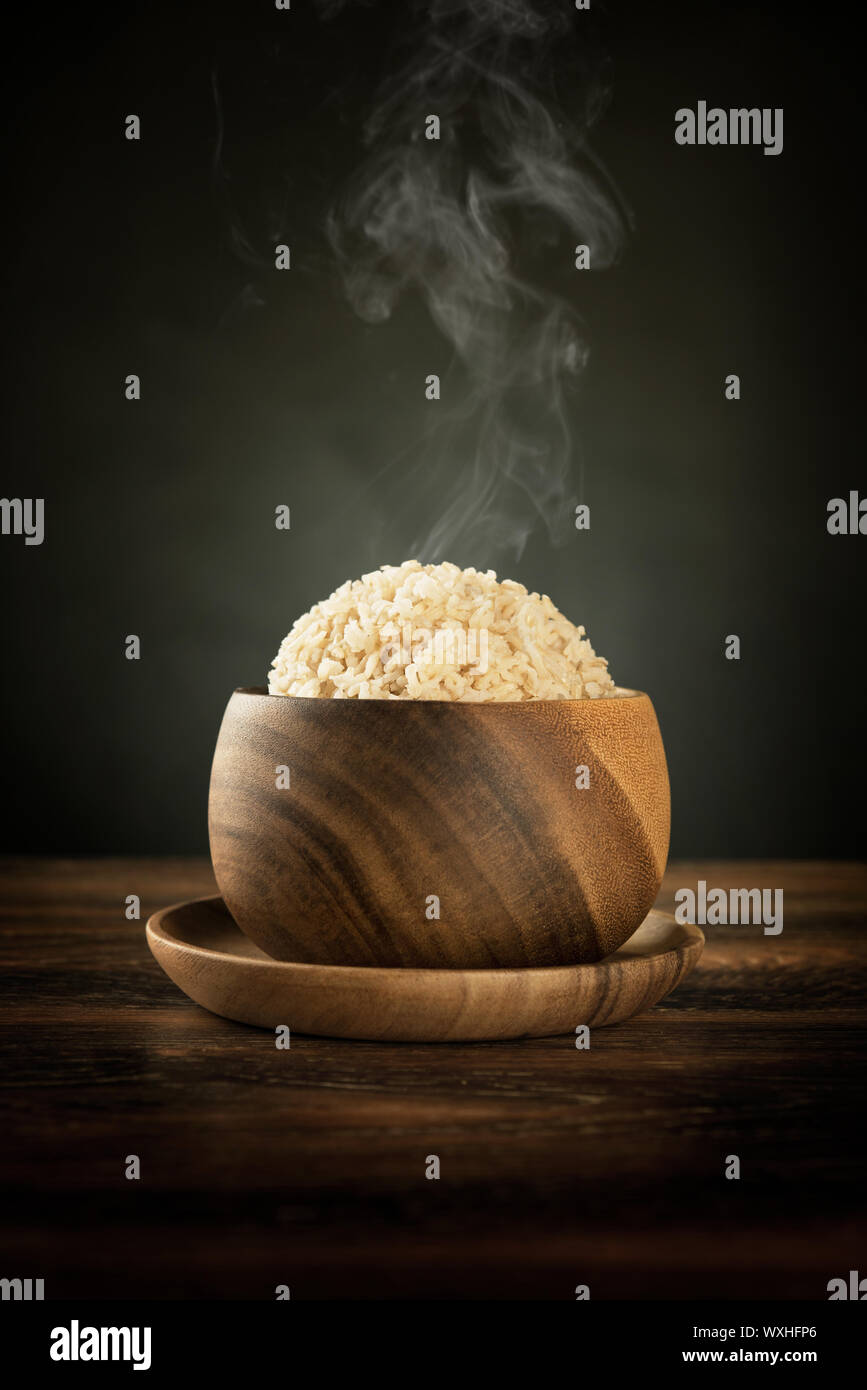 Cooked organic basmati brown rice in wooden bowl with hot steam smoke ...