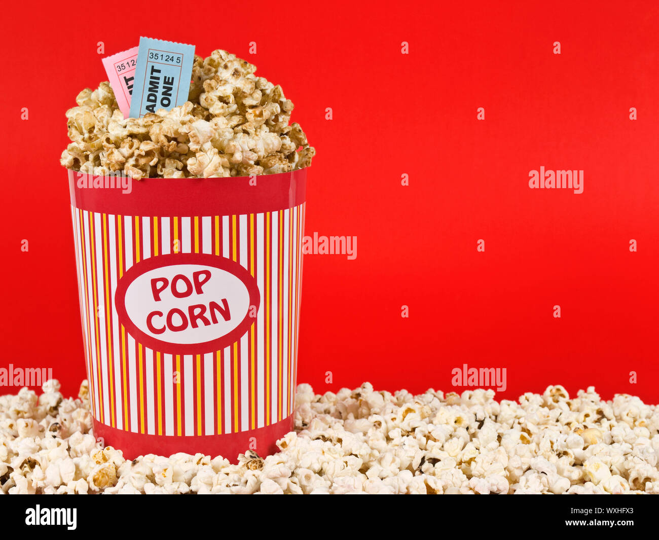A popcorn bucket over a red background. Movie stubs sitting over the ...