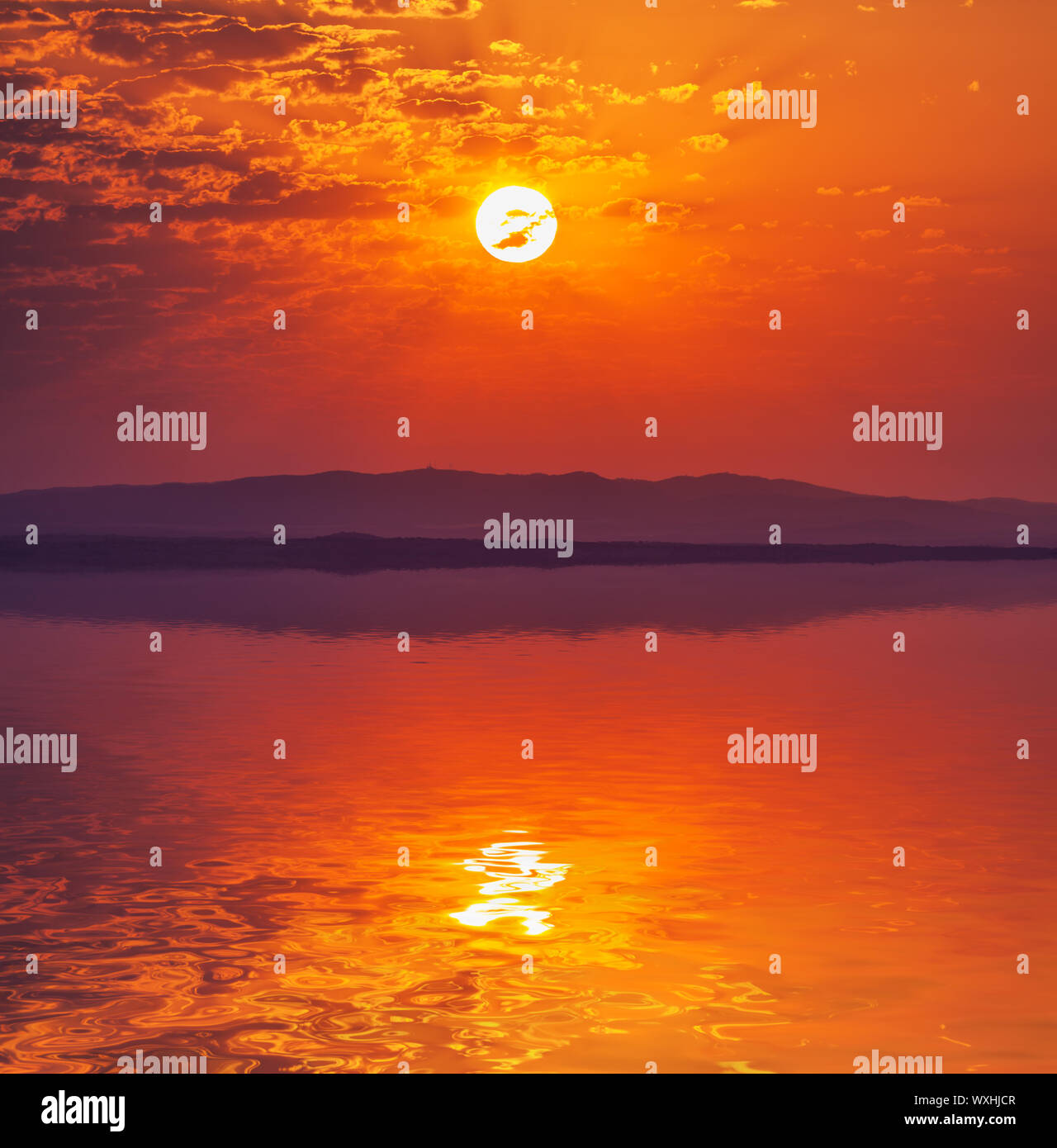 Vibrant rising sun at dawn over water, beautiful scenery Stock Photo ...