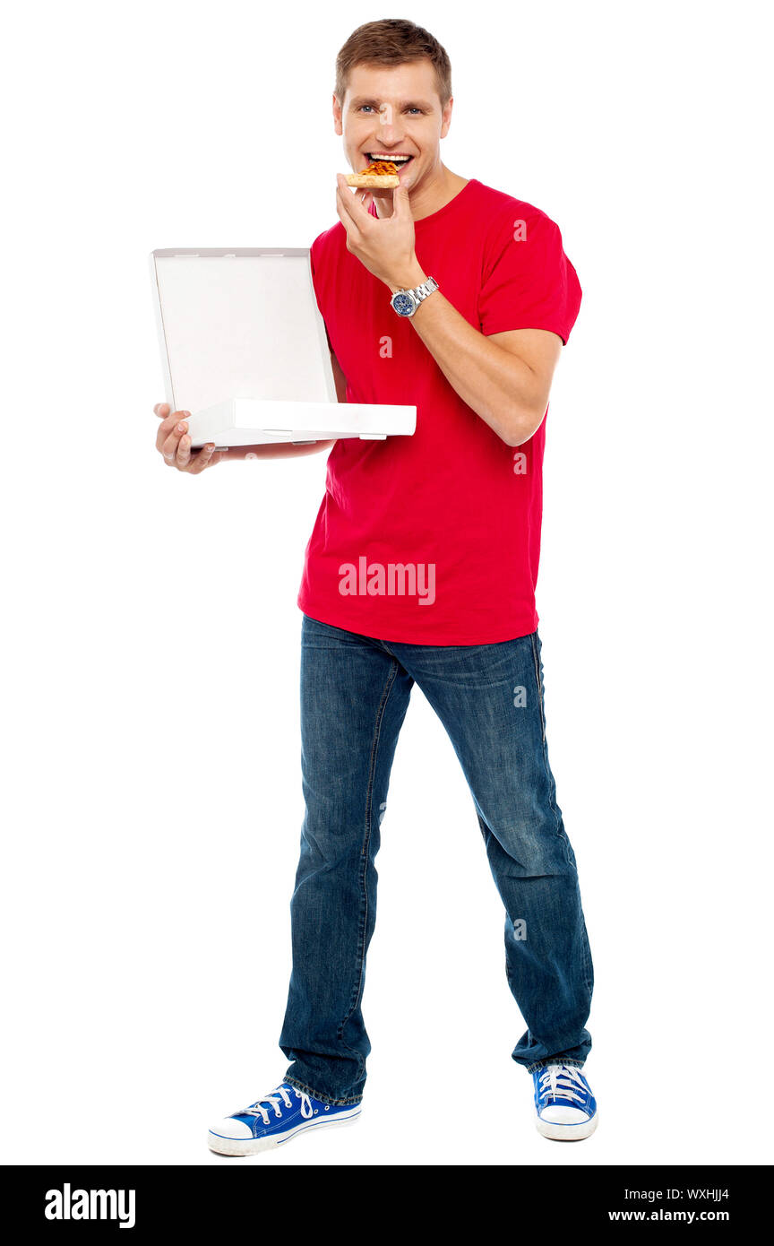 Causal smart guy holding pizza box and eating a piece. Full length ...