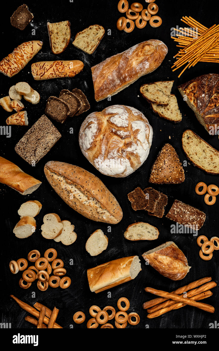 Assortment of different types of bread on a black background. Top view ...