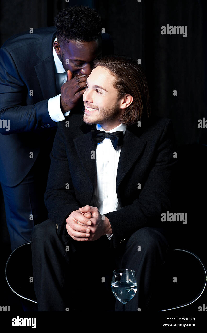 African guy whispering something into the ears of his boss during a ...