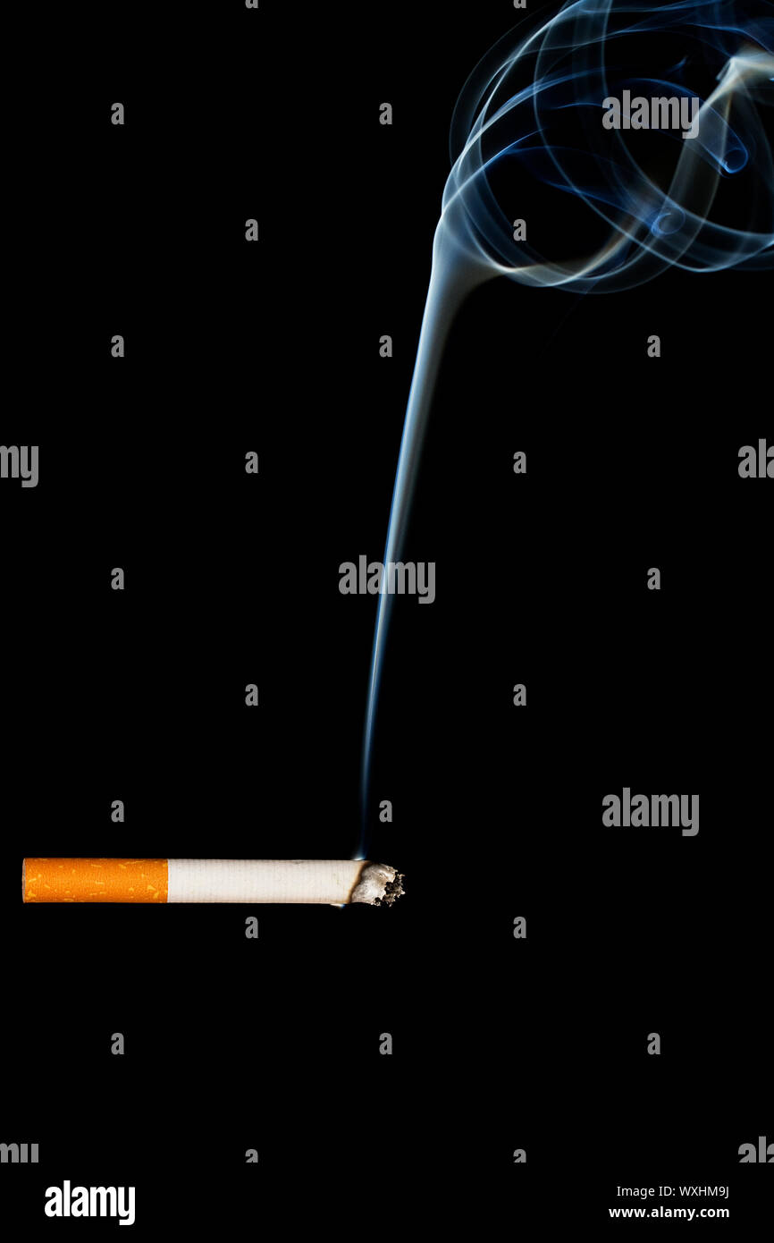 a smoking cigarette in front of black background Stock Photo - Alamy