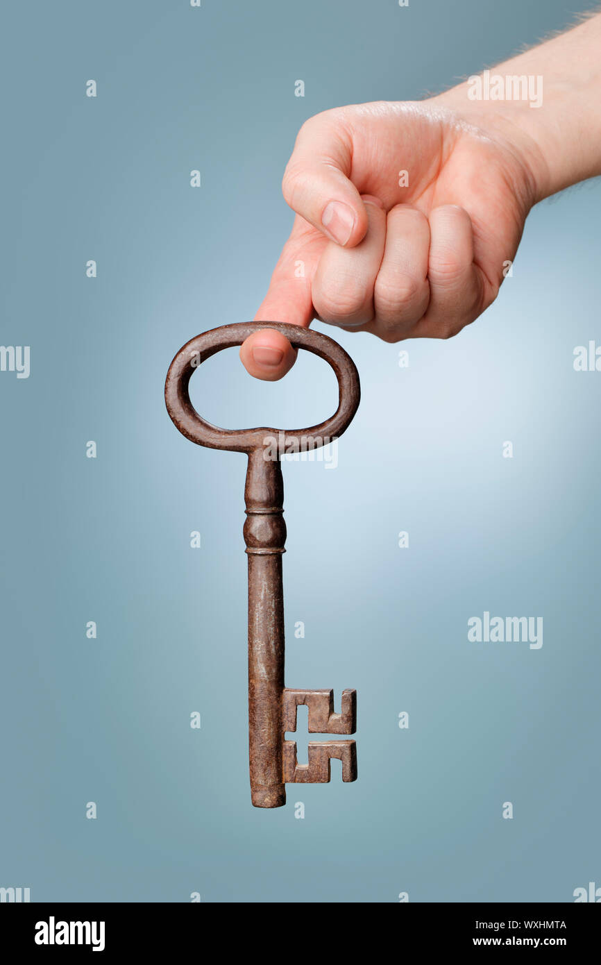 A Large old antique skeleton key hanging from a finger Stock Photo - Alamy