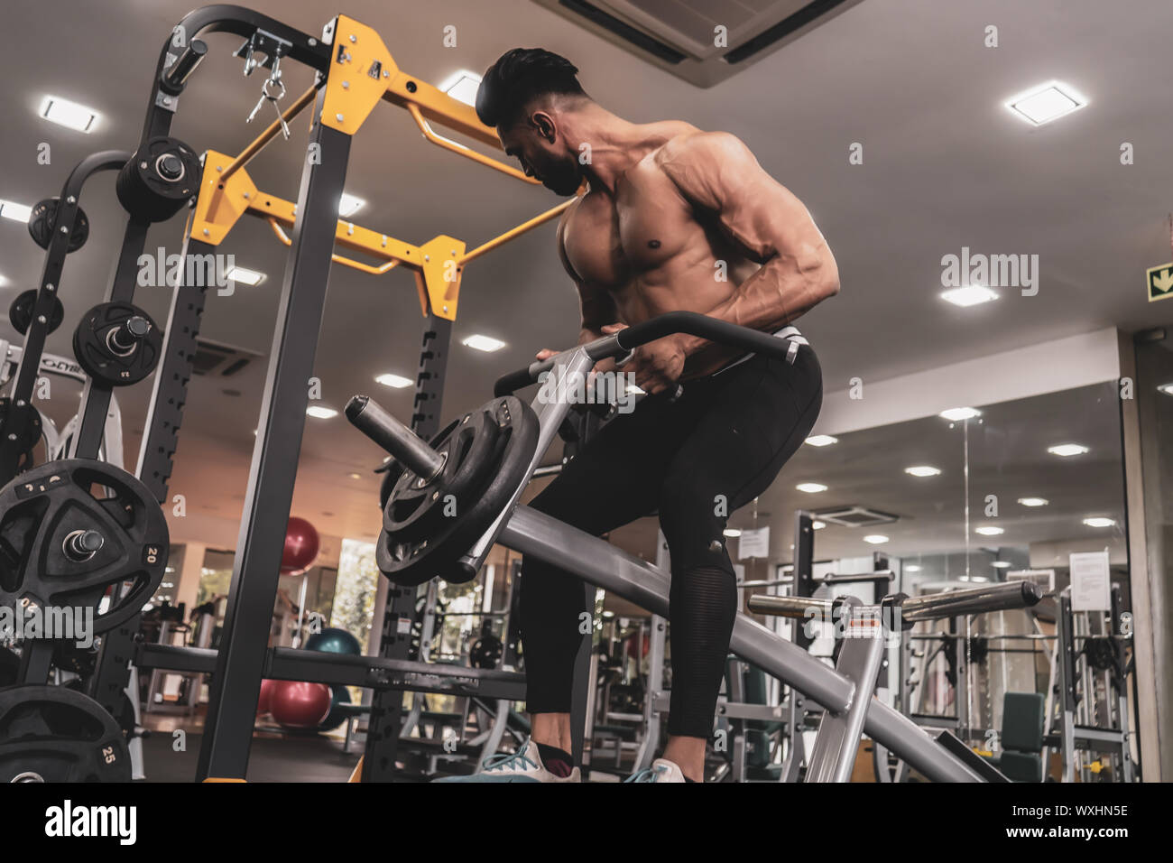 Muscular men exercising with weights. He is performing T bar rows for ...