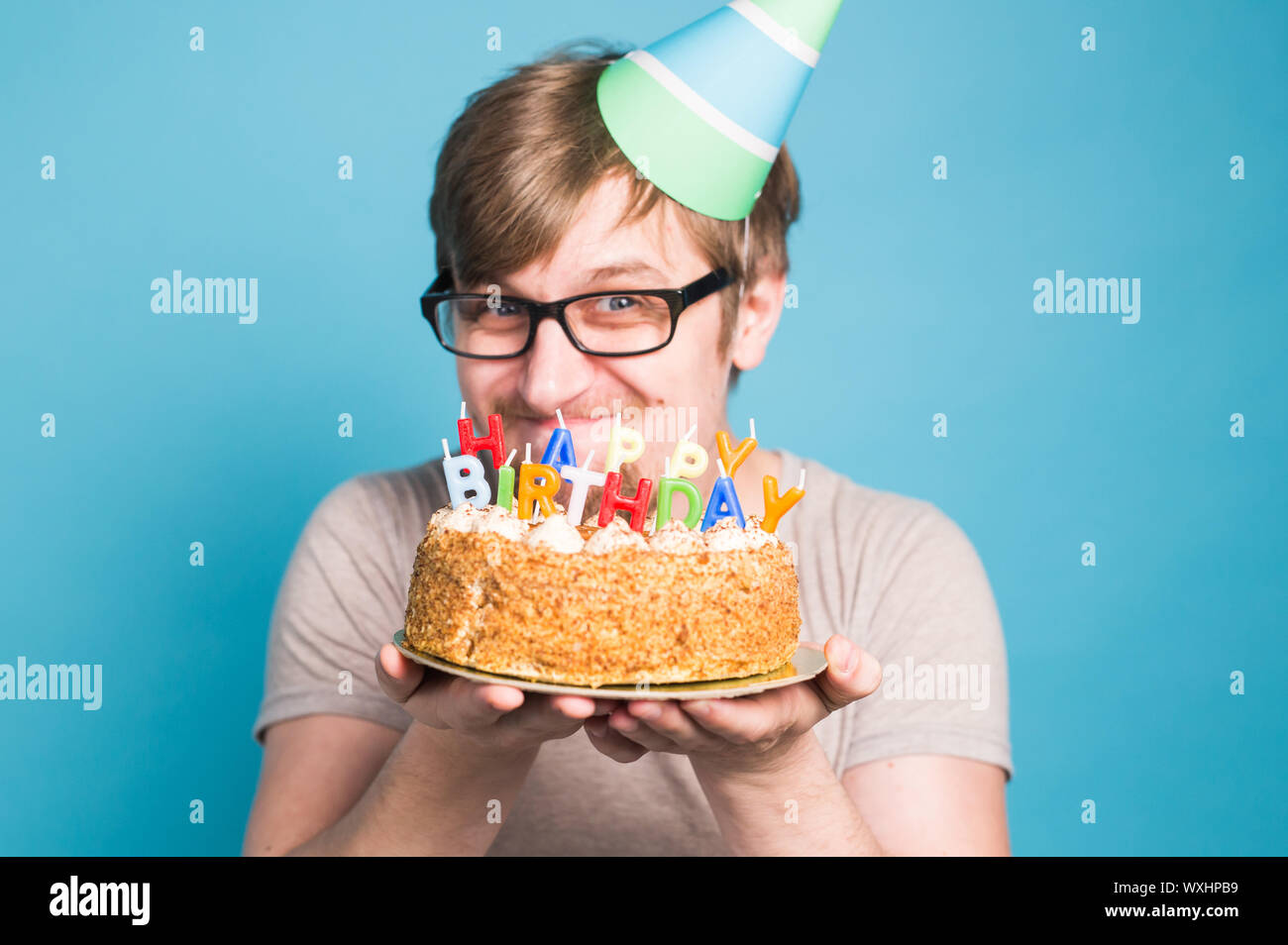 Funny crazy young man in a greeting paper hat wants to bite off a piece ...
